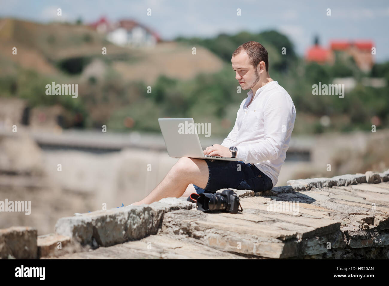 Man using a modern portable computer on the park, street on background ...