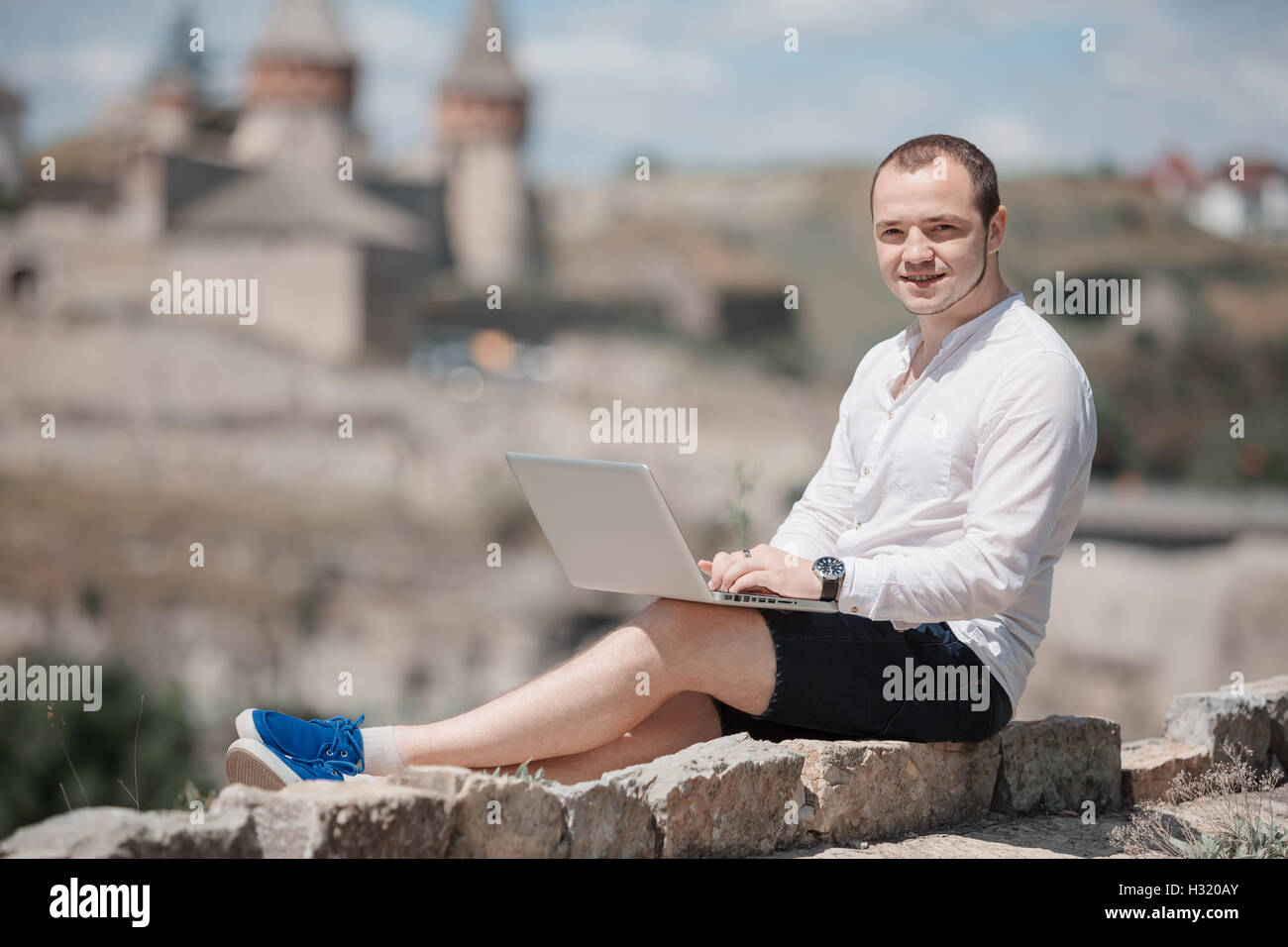 Man using a modern portable computer on the park, street on background ...