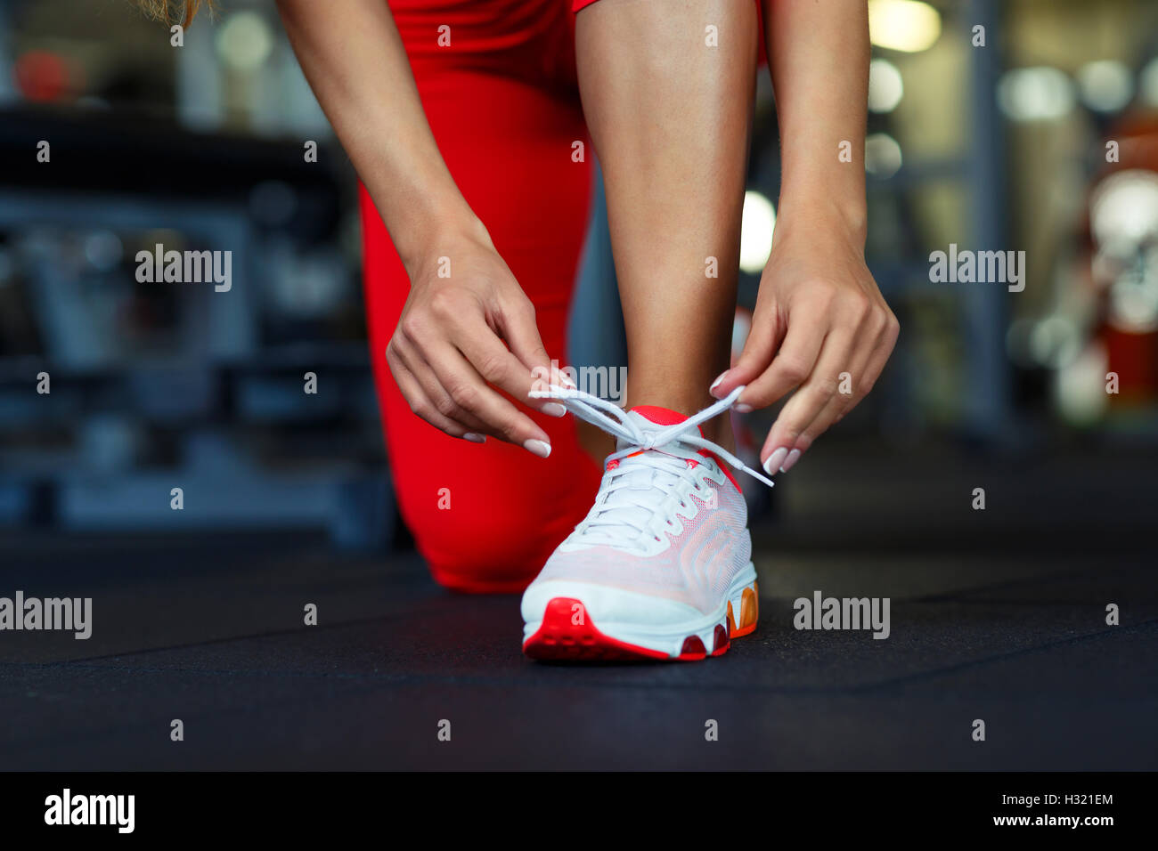 Running shoes - woman tying shoe laces. Closeup of fitness woman getting ready for engage in the ...