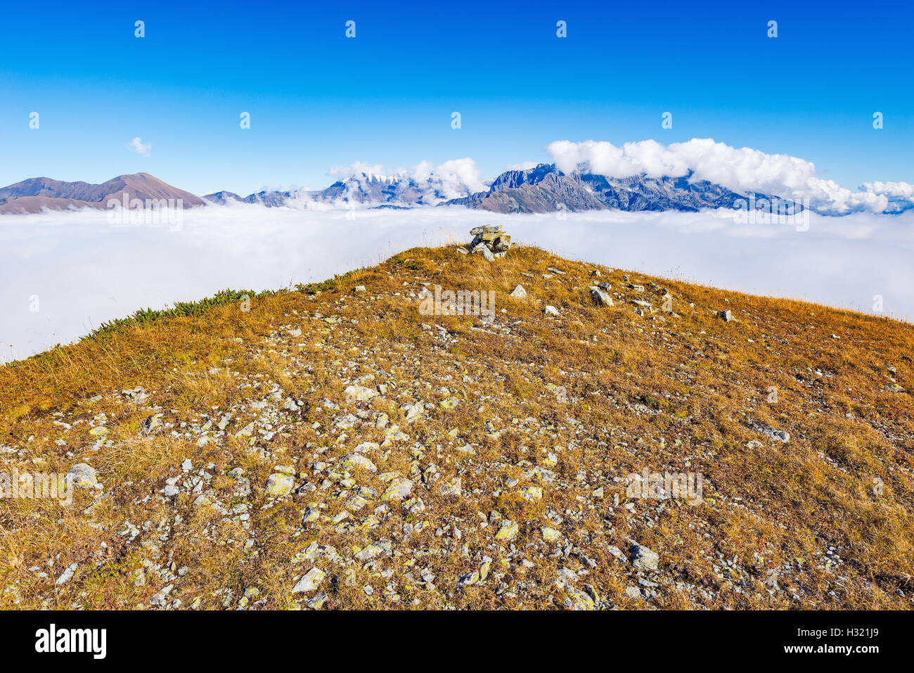 Small tower of stones on the top of the mountain above the clouds ...