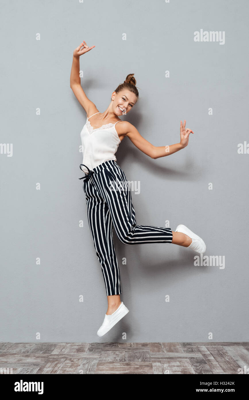 Full length portrait of a cheerful cute woman jumping isolated on a ...