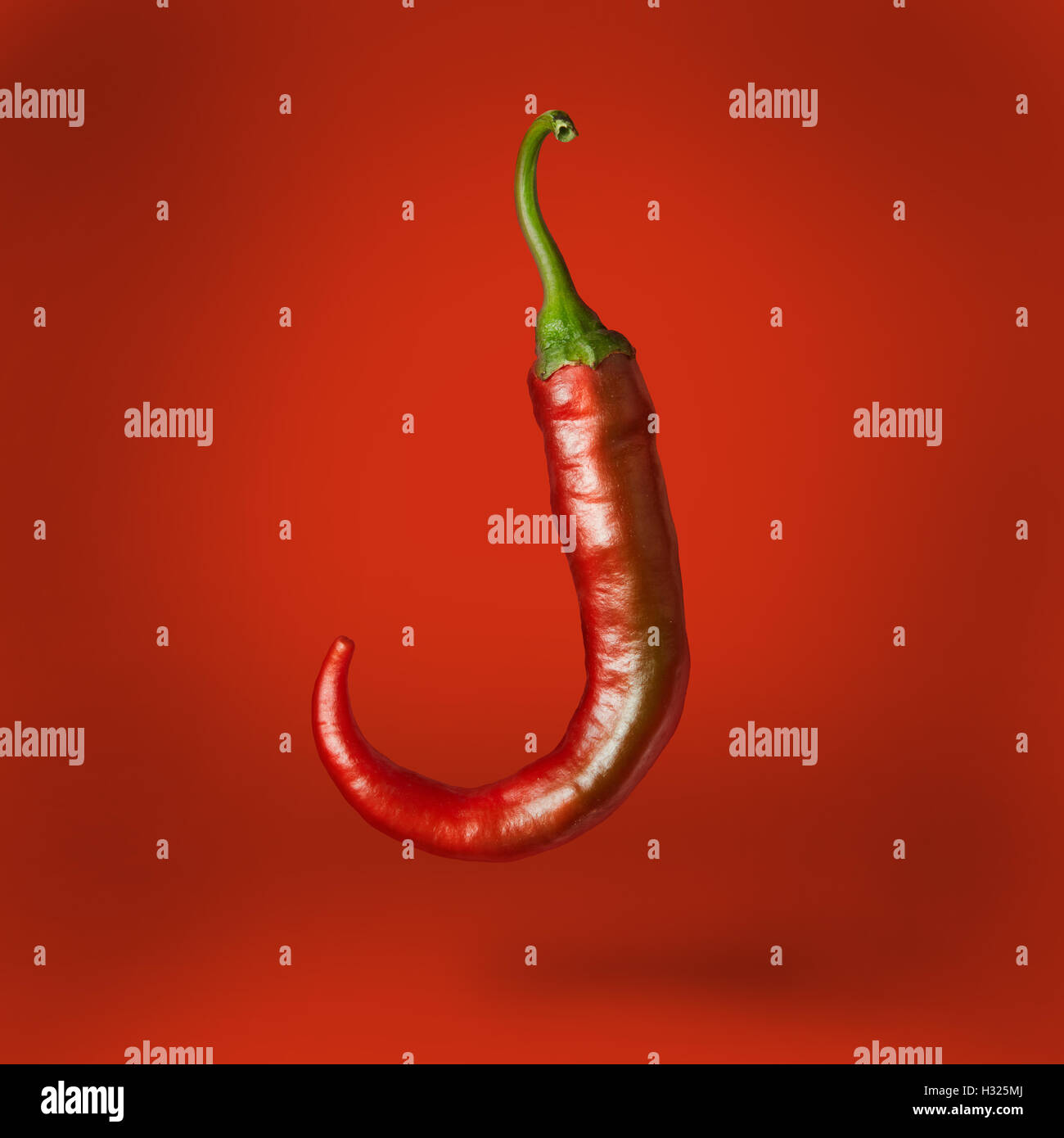 Hot chilli pepper floating over red background Stock Photo - Alamy