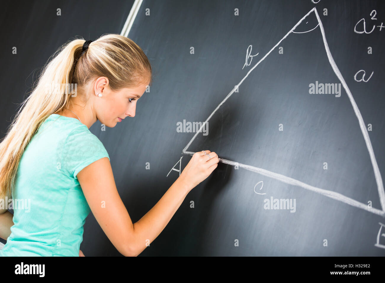 Pretty young elementary school/college teacher writing on the ch Stock ...