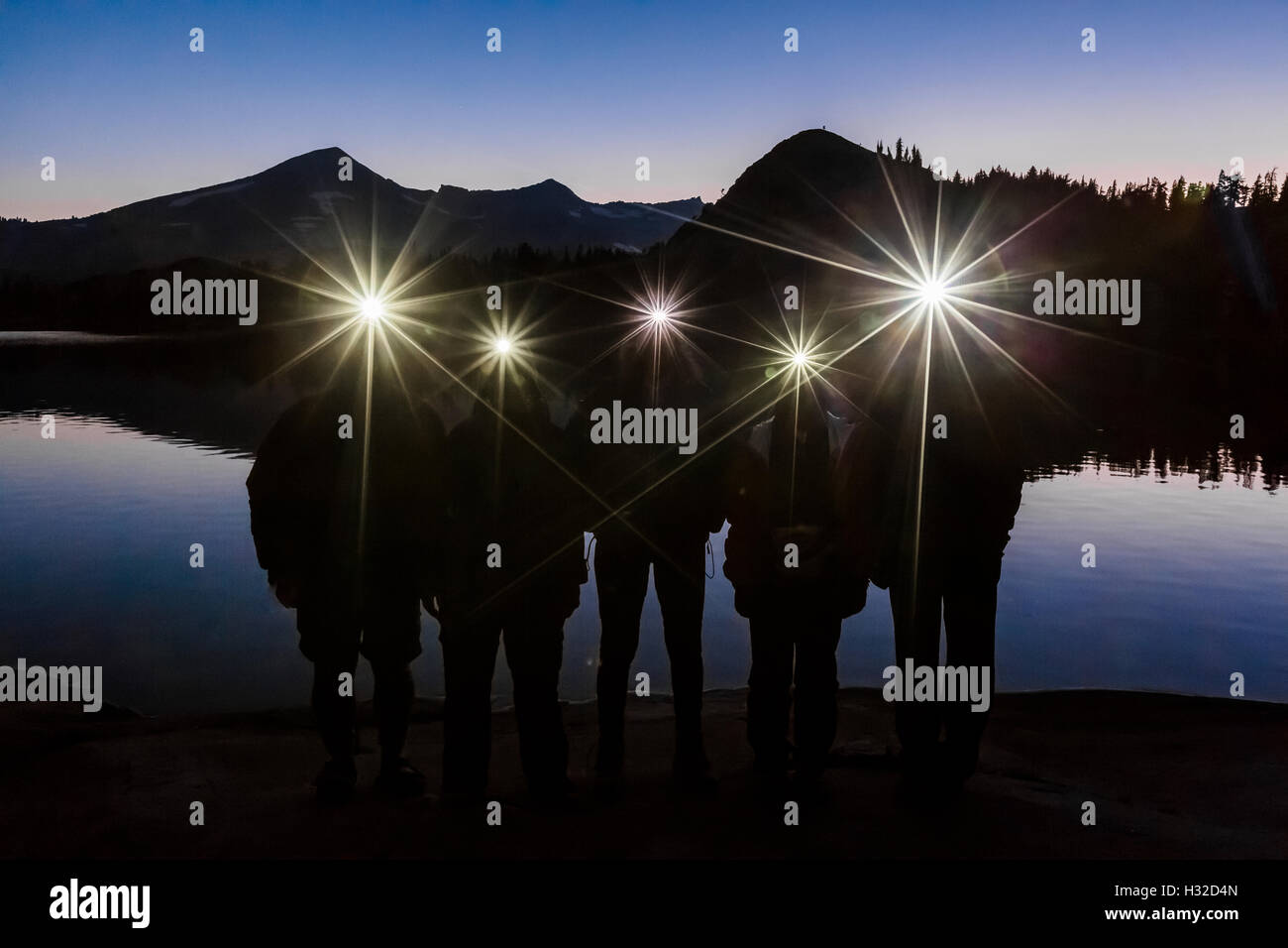 Group of five hikers with headlamps at deep twilight along Lake of the ...