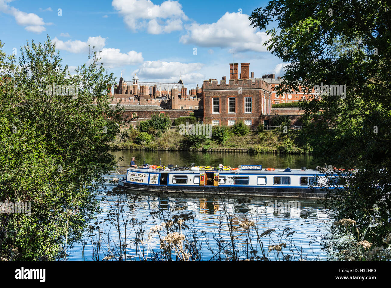 A narrowboat passing Hampton Court Palace on the River Thames in Surrey ...