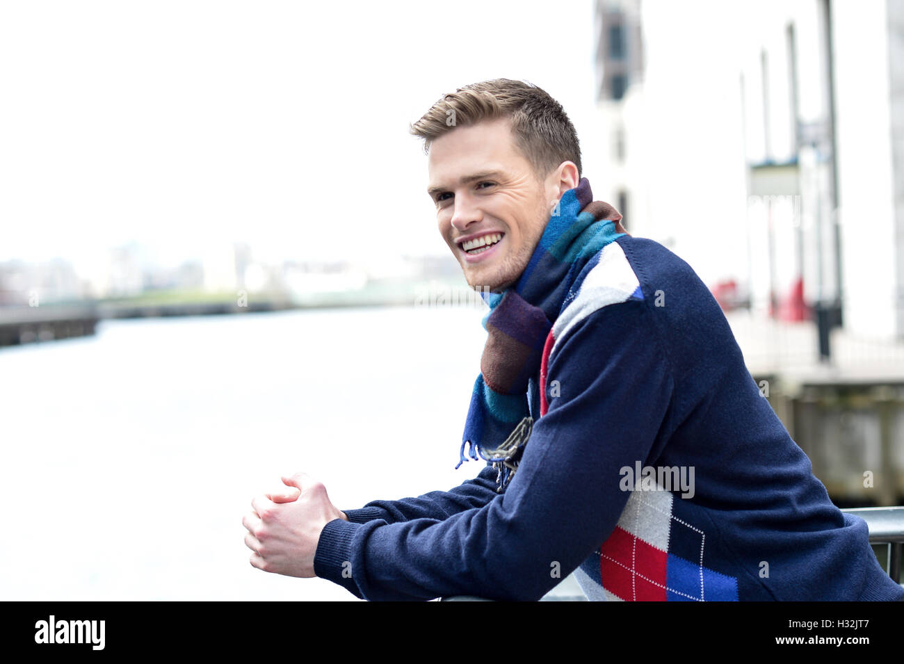 Handsome man leaning on railing at river Stock Photo - Alamy