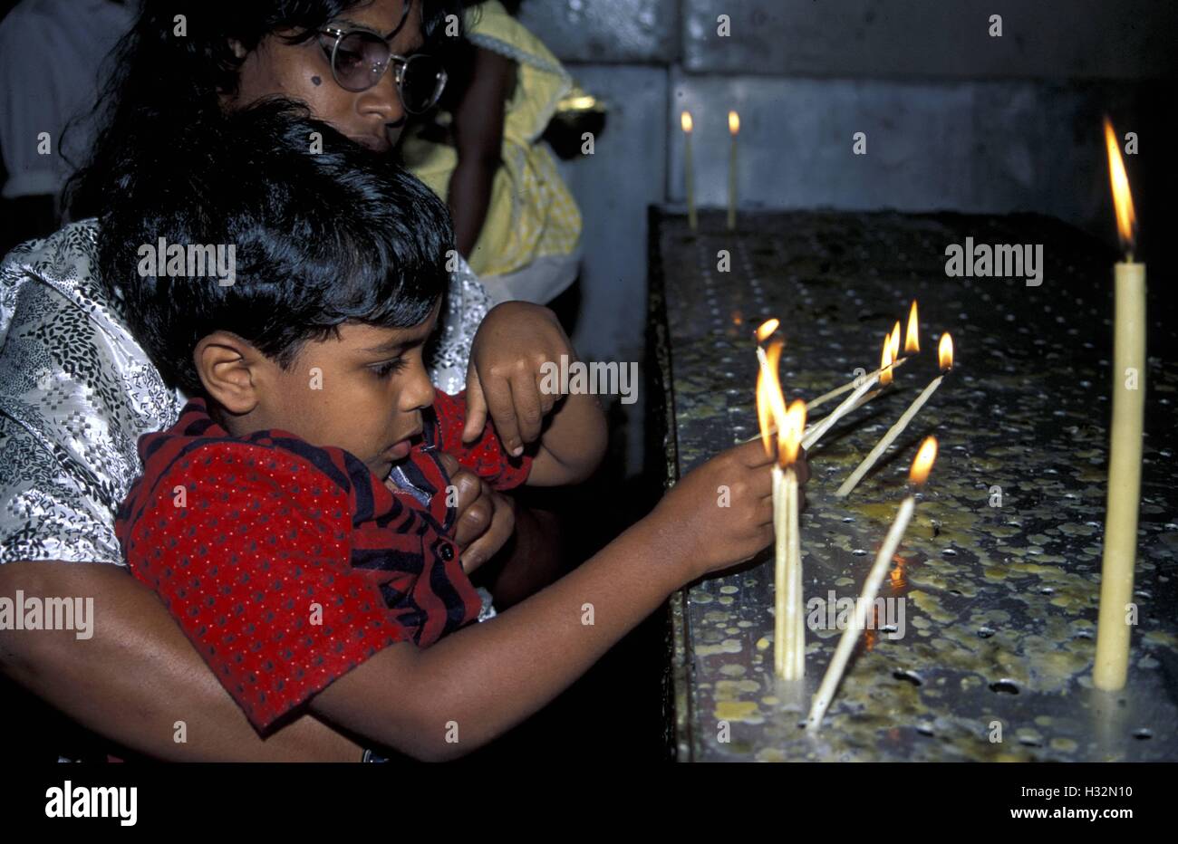 A boy places a candle before an icon of the Virgin Mary in Colombo, Sri ...