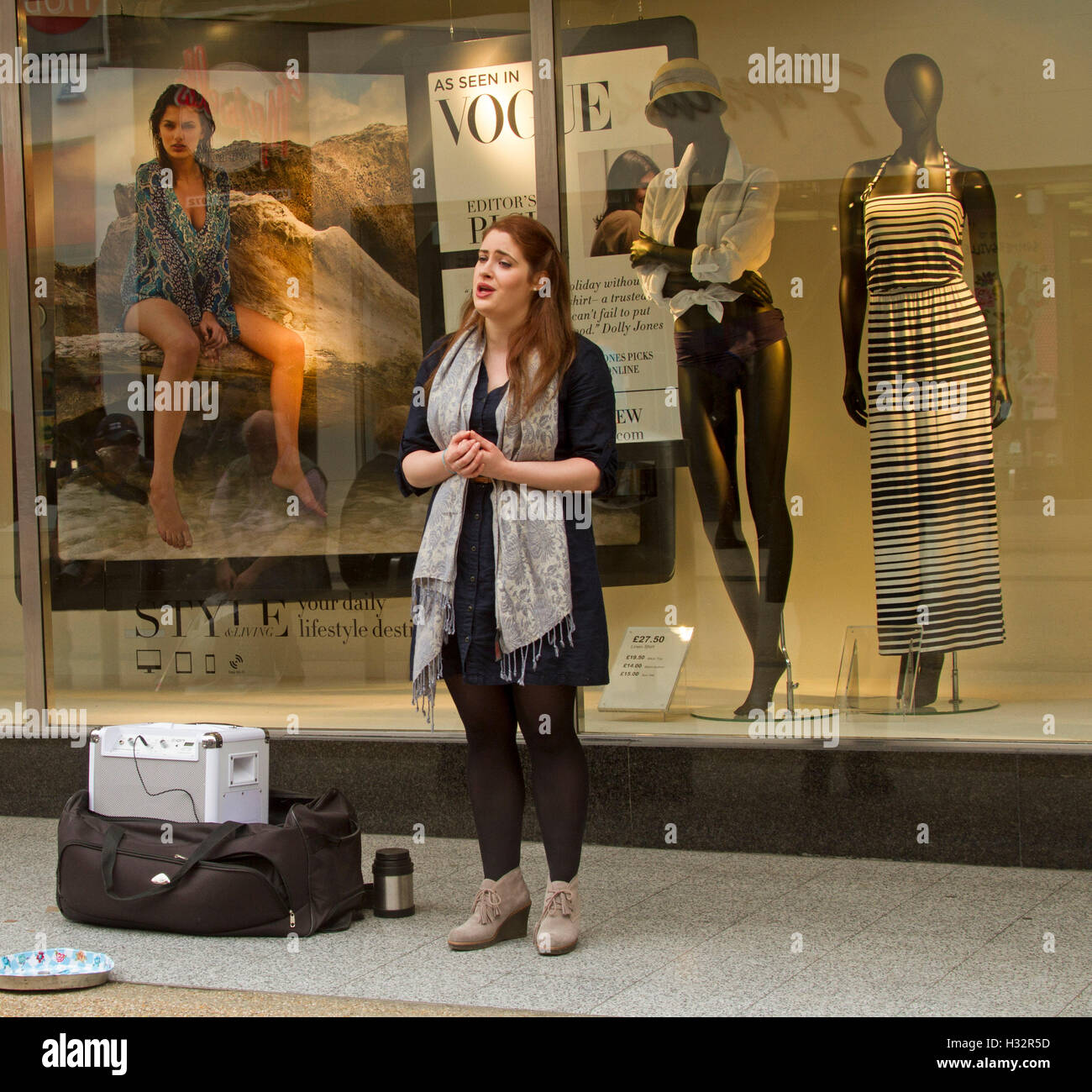 Female opera singer busking outside department store window with ...
