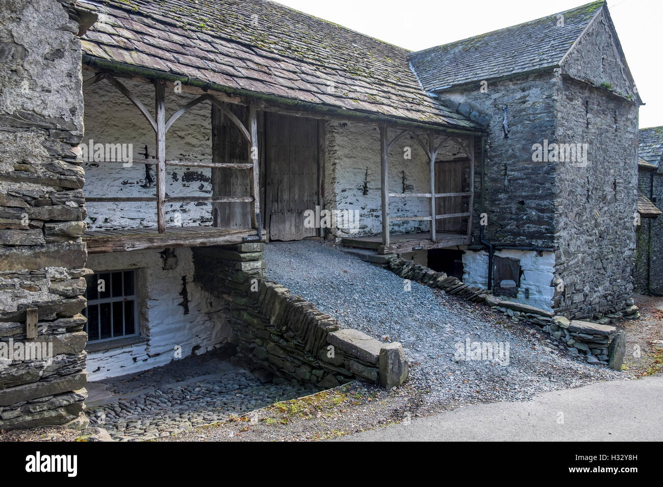 An very old stone farm building with broken windows and wooden doors ...