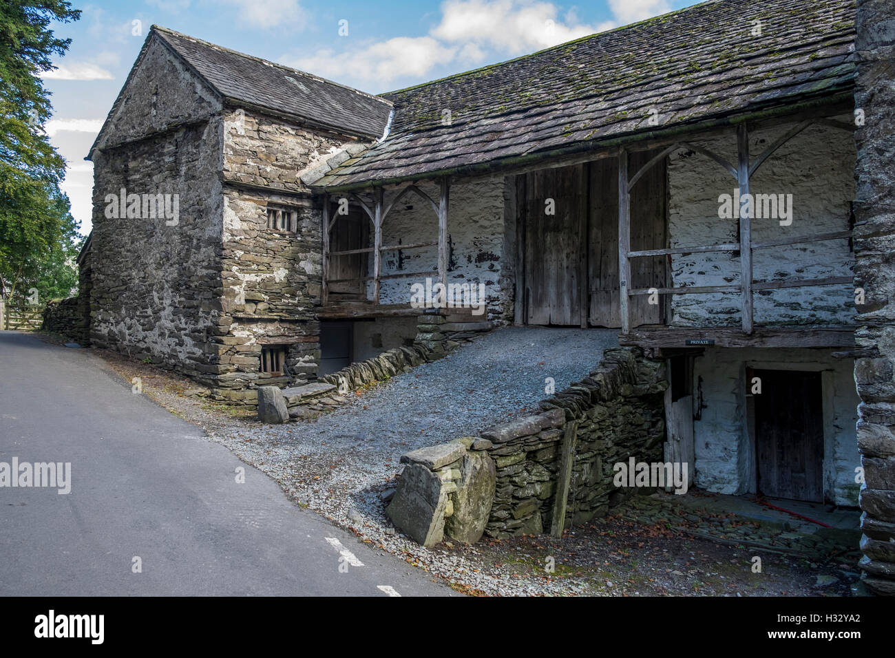An very old stone farm building with broken windows and wooden doors ...