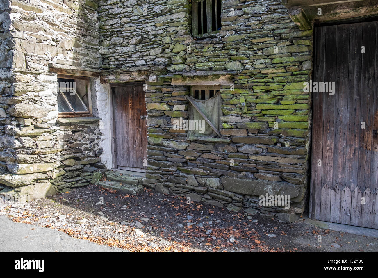 An very old stone farm building with broken windows and wooden doors ...