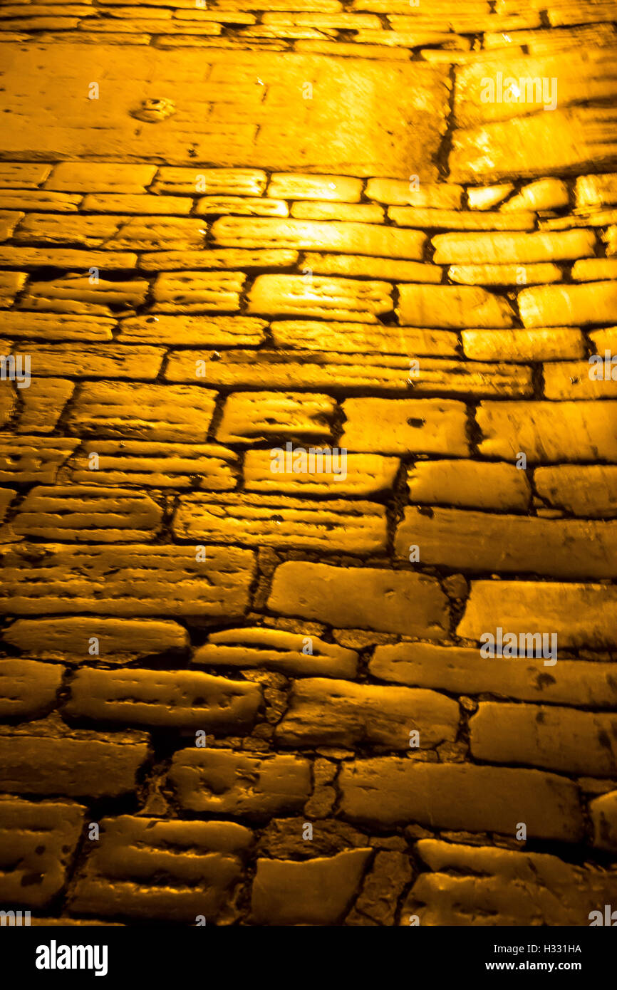 Cobbles/ paving stones given a golden glow under at night time lighting ...