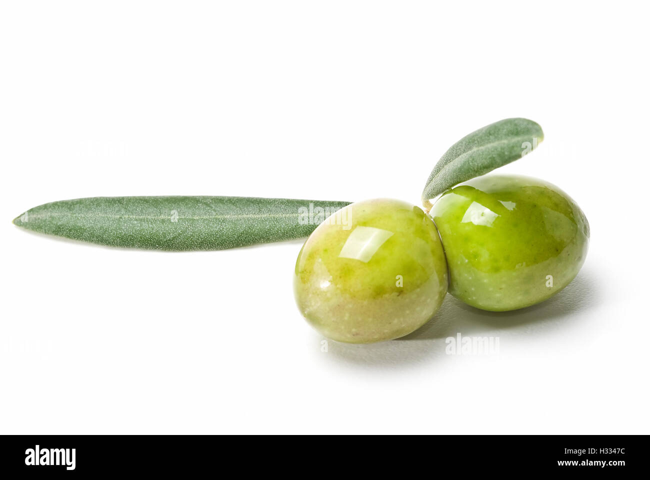 Two green olives with leaves isolated over white Stock Photo - Alamy