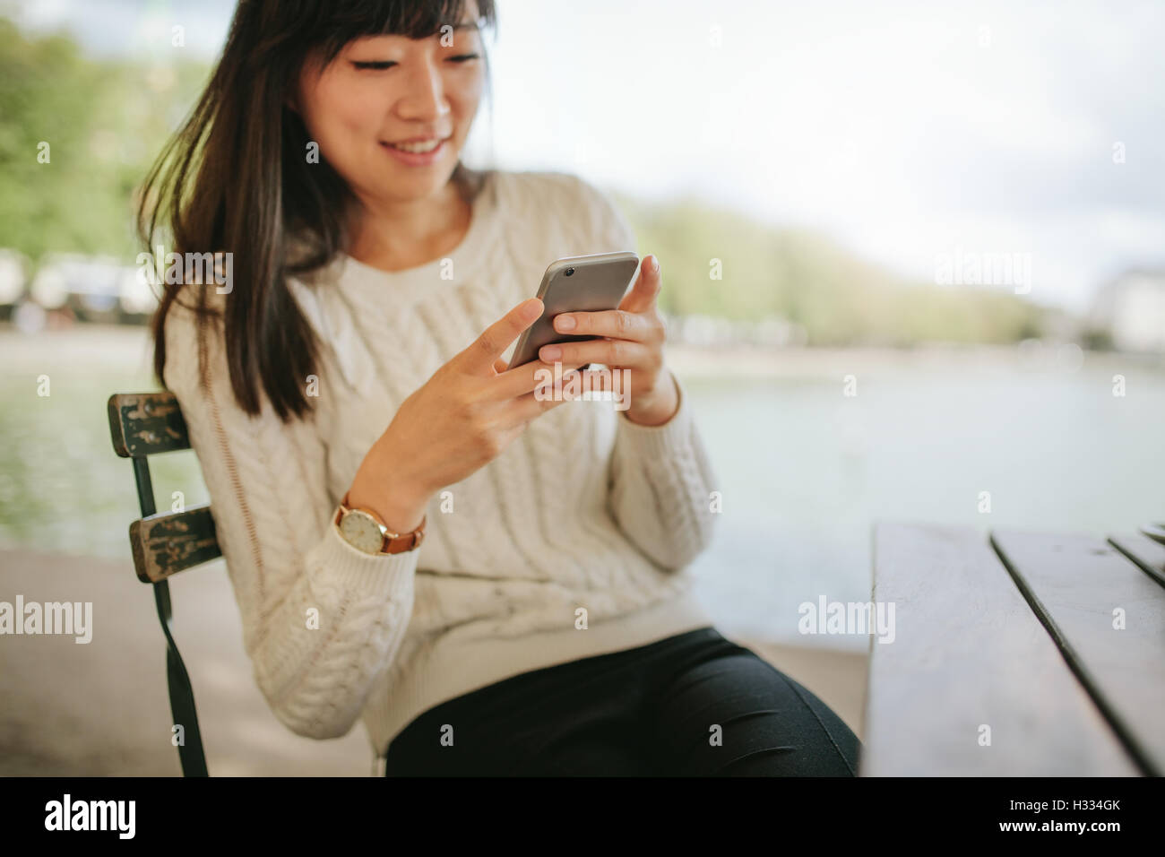 Shot of happy young female using mobile phone at outdoor cafe. Young ...