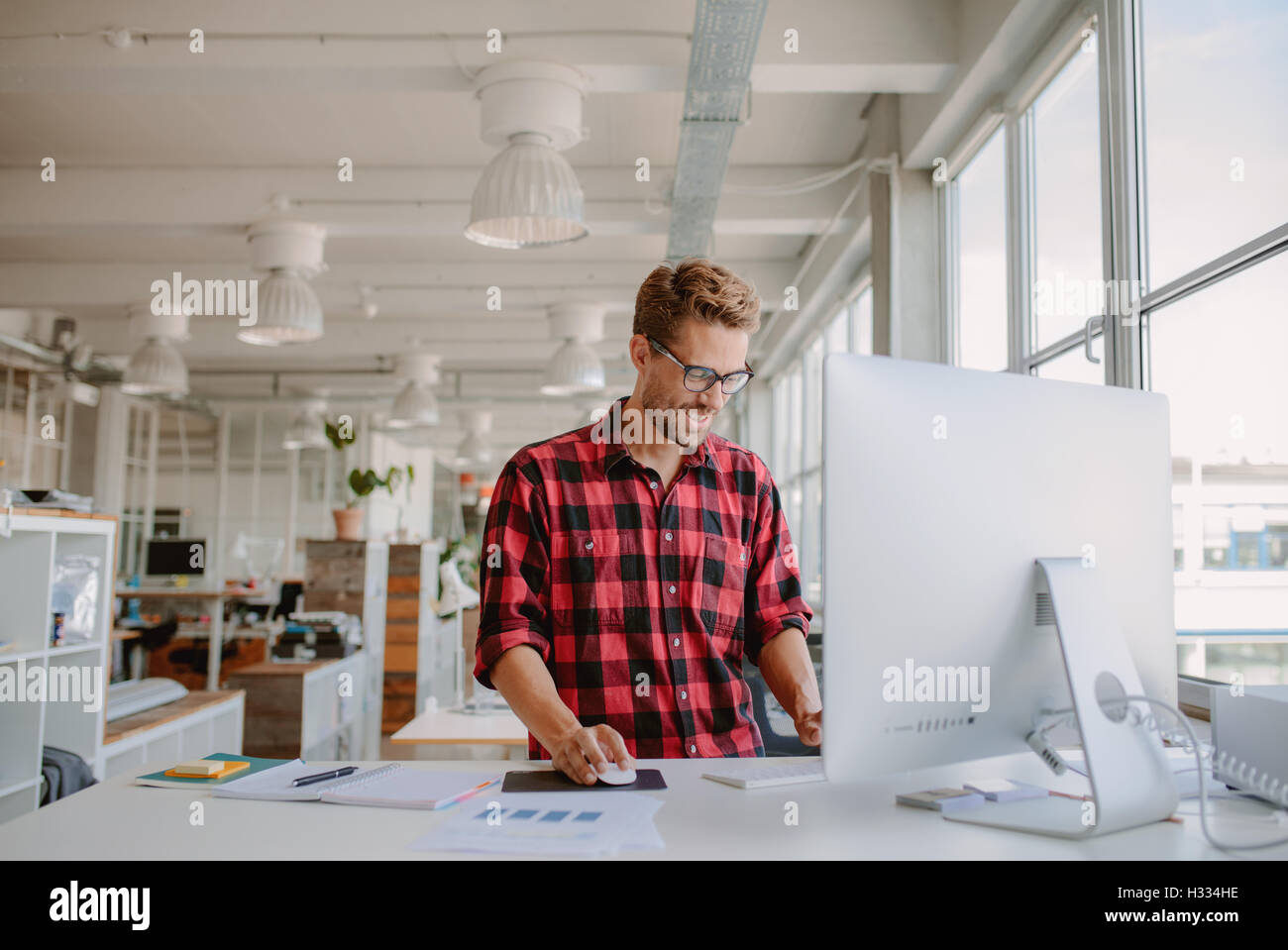 Shot of happy young man working on desktop computer in modern workplace ...