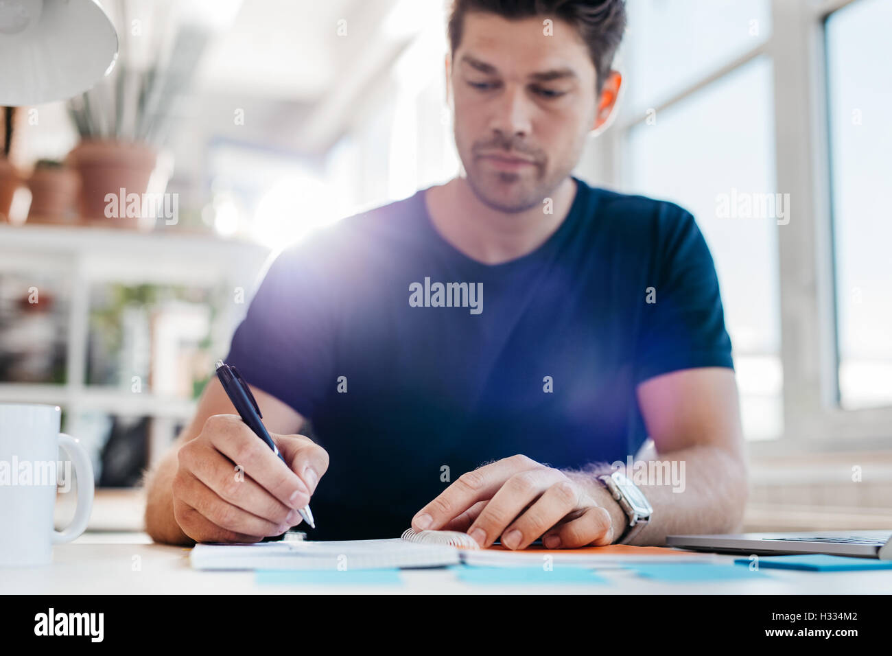 Young male business executive writing down some important notes in ...