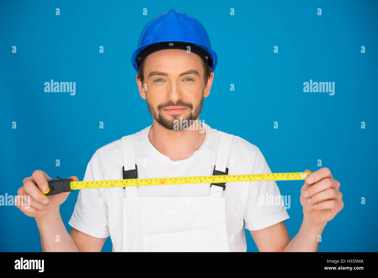 Smiling workman holding a tape measure Stock Photo - Alamy