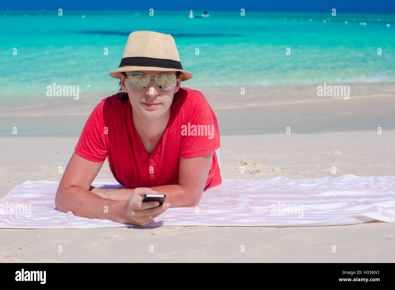 Young guy with cellphone on tropical white beach Stock Photo - Alamy