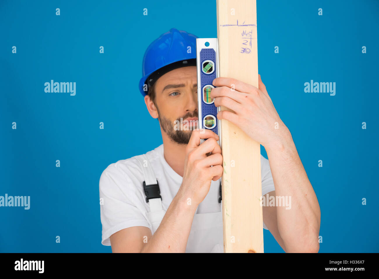Builder holding a spirit level and plank of wood Stock Photo - Alamy