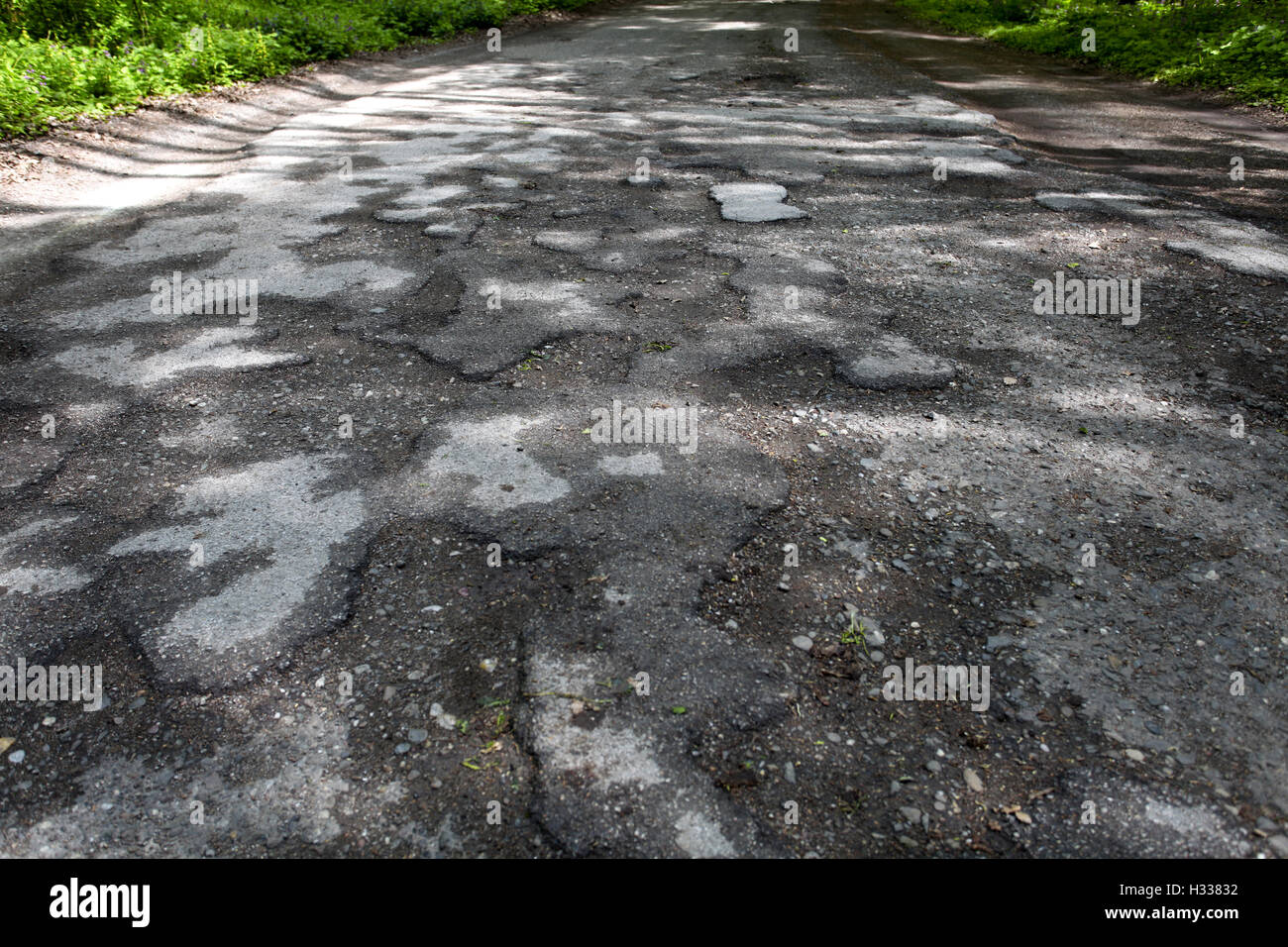 Damaged road full of cracked potholes in pavement Stock Photo - Alamy