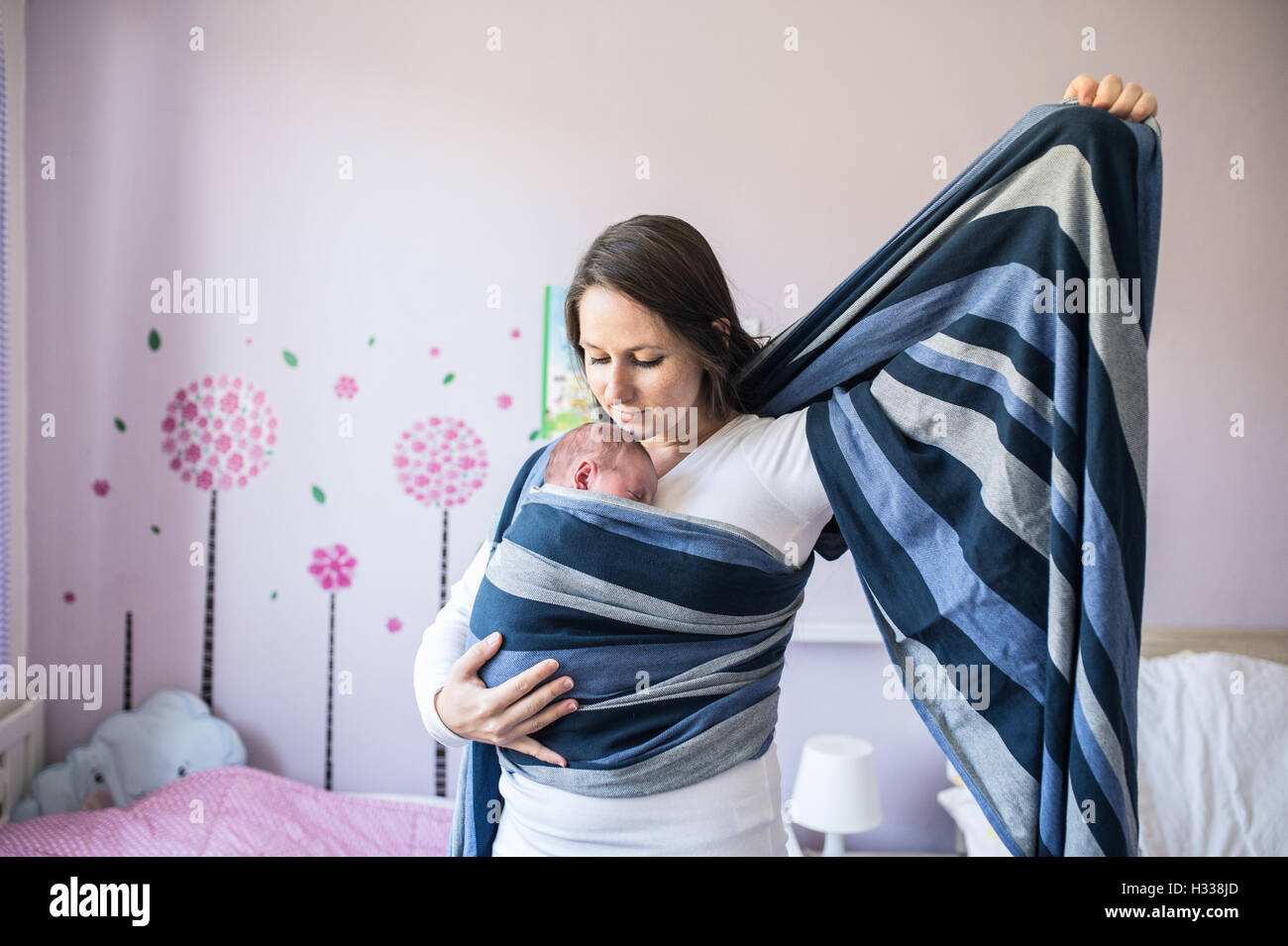 Beautiful young mother wrapping her son into sling Stock Photo - Alamy