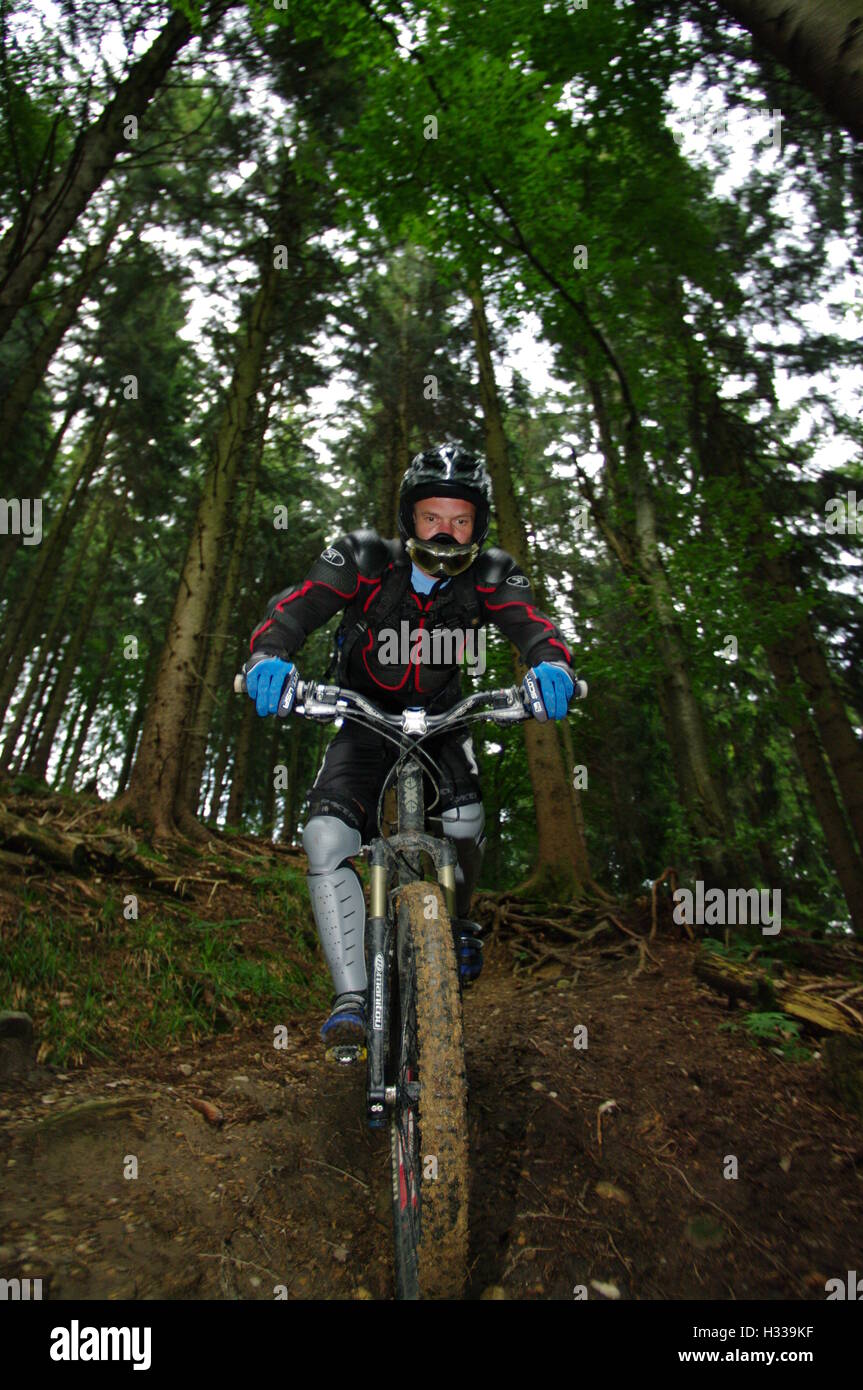 Downhill mountain biker riding on a trail through a forest Stock Photo ...