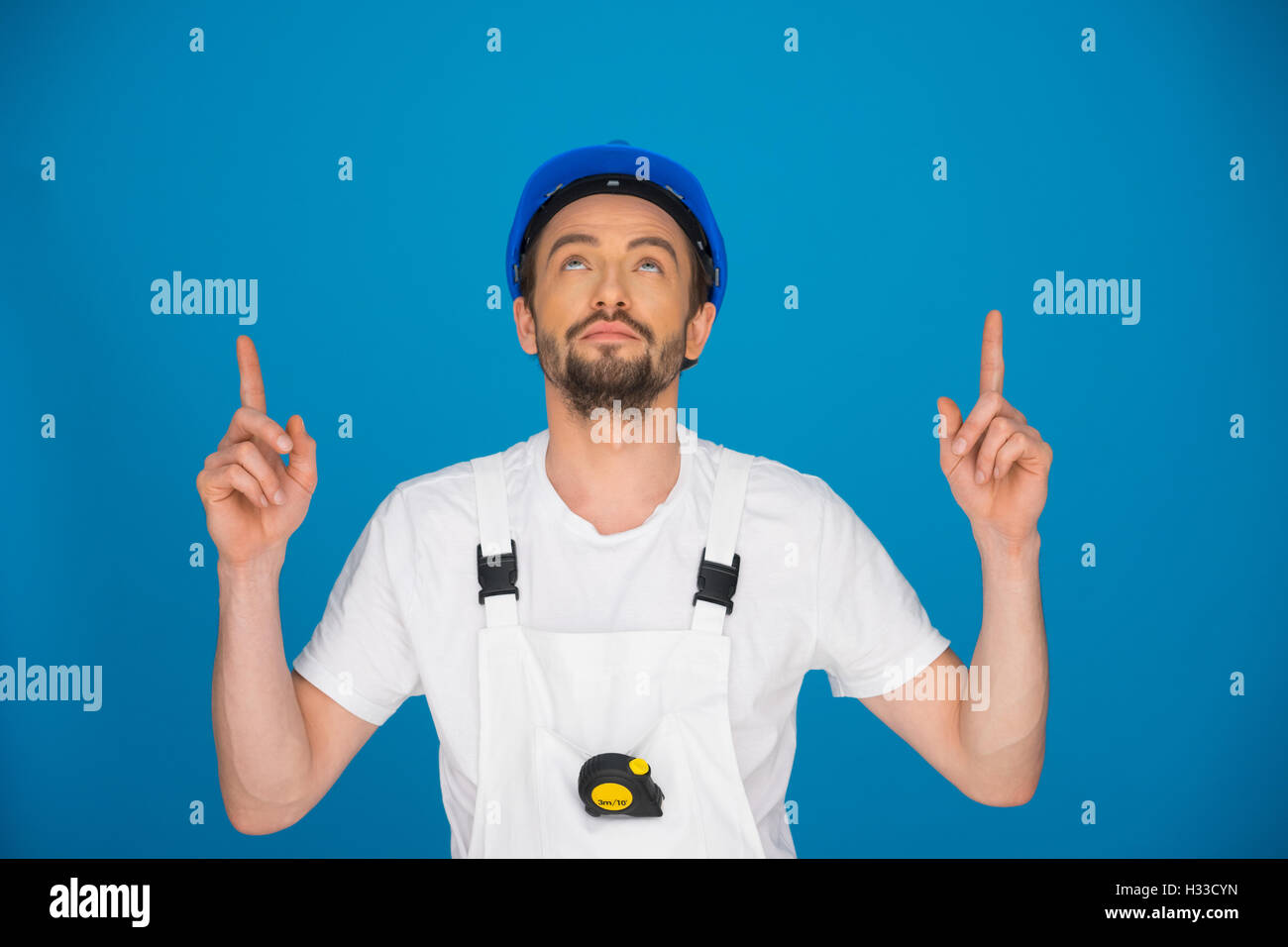 Workman in a hardhat pointing above his head Stock Photo - Alamy