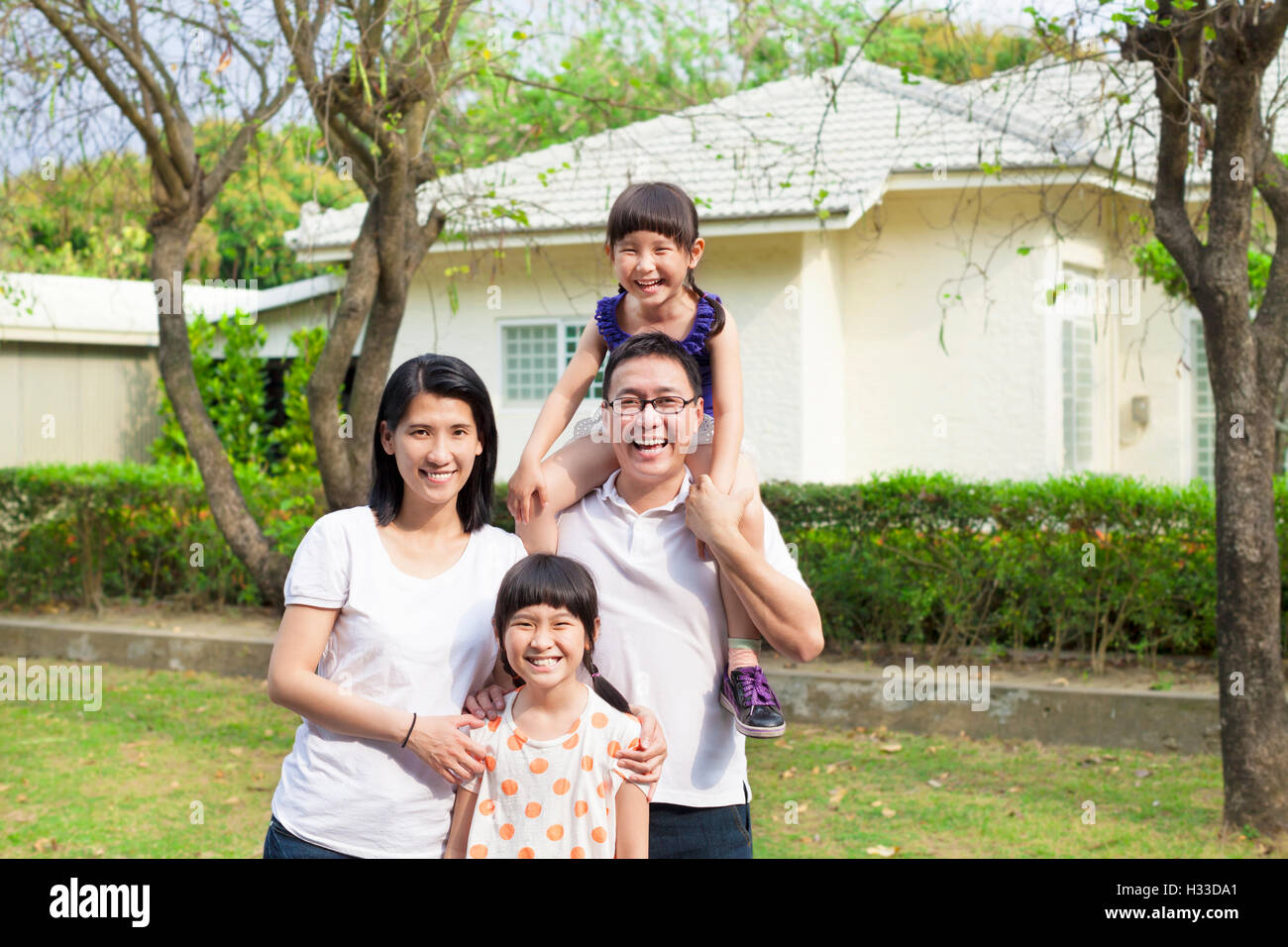 Happy family standing before their house Stock Photo - Alamy
