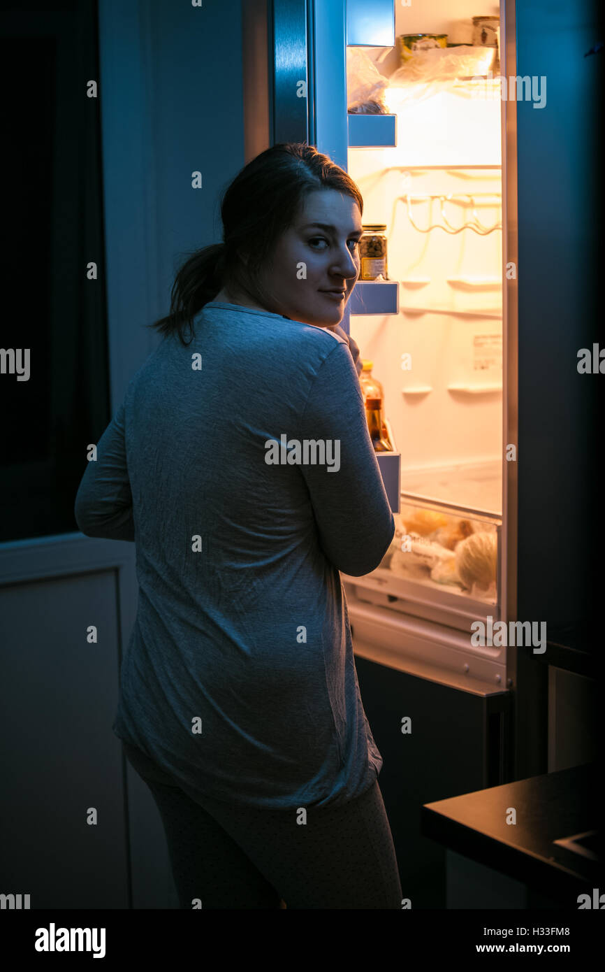 photo of woman looking in fridge at late night Stock Photo - Alamy