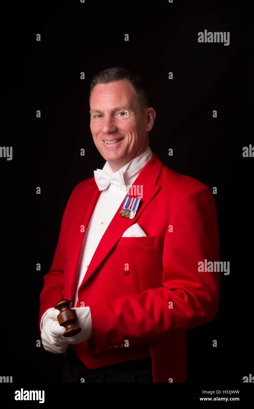 Toastmaster against a black background in traditional red jacket with ...