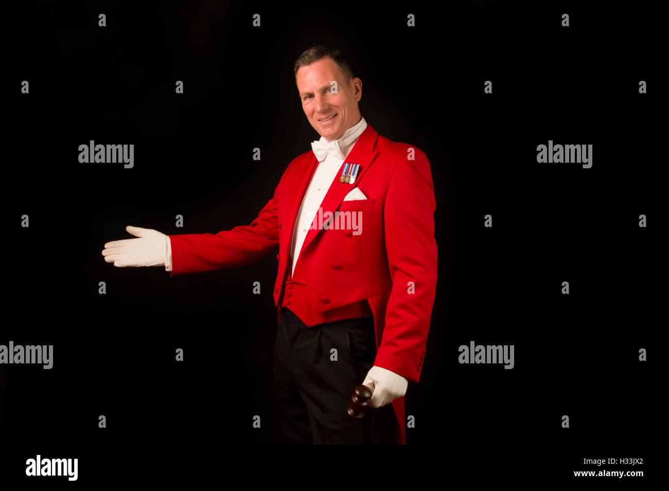 Toastmaster against a black background in traditional red jacket with ...