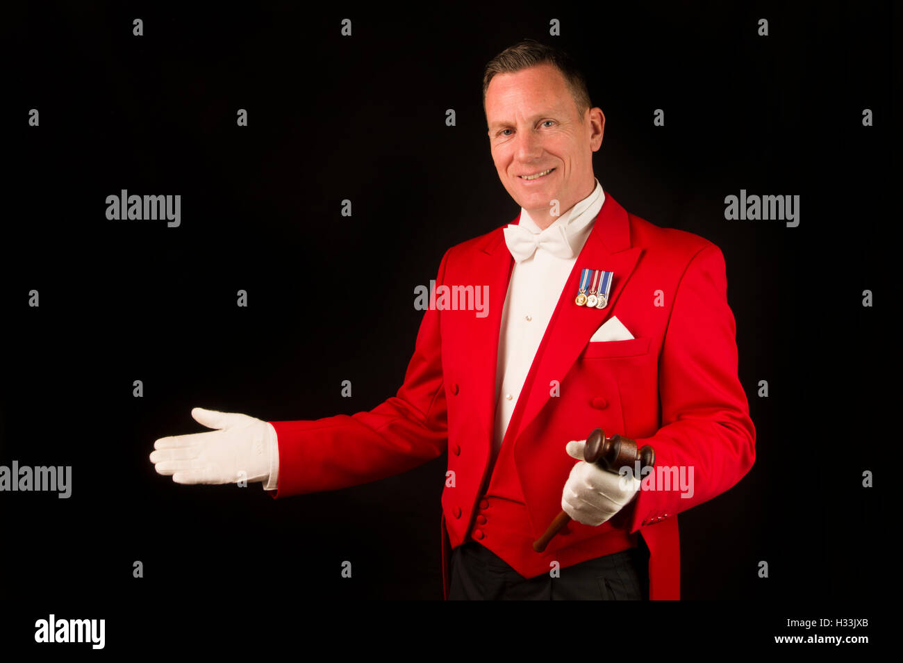 Toastmaster against a black background in traditional red jacket with ...