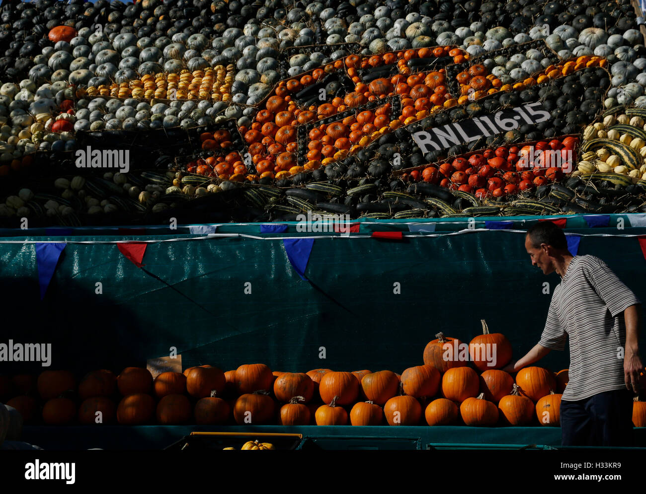 Worker stacks pumpkins with RNLI Lifeboat picture made from squashes ...