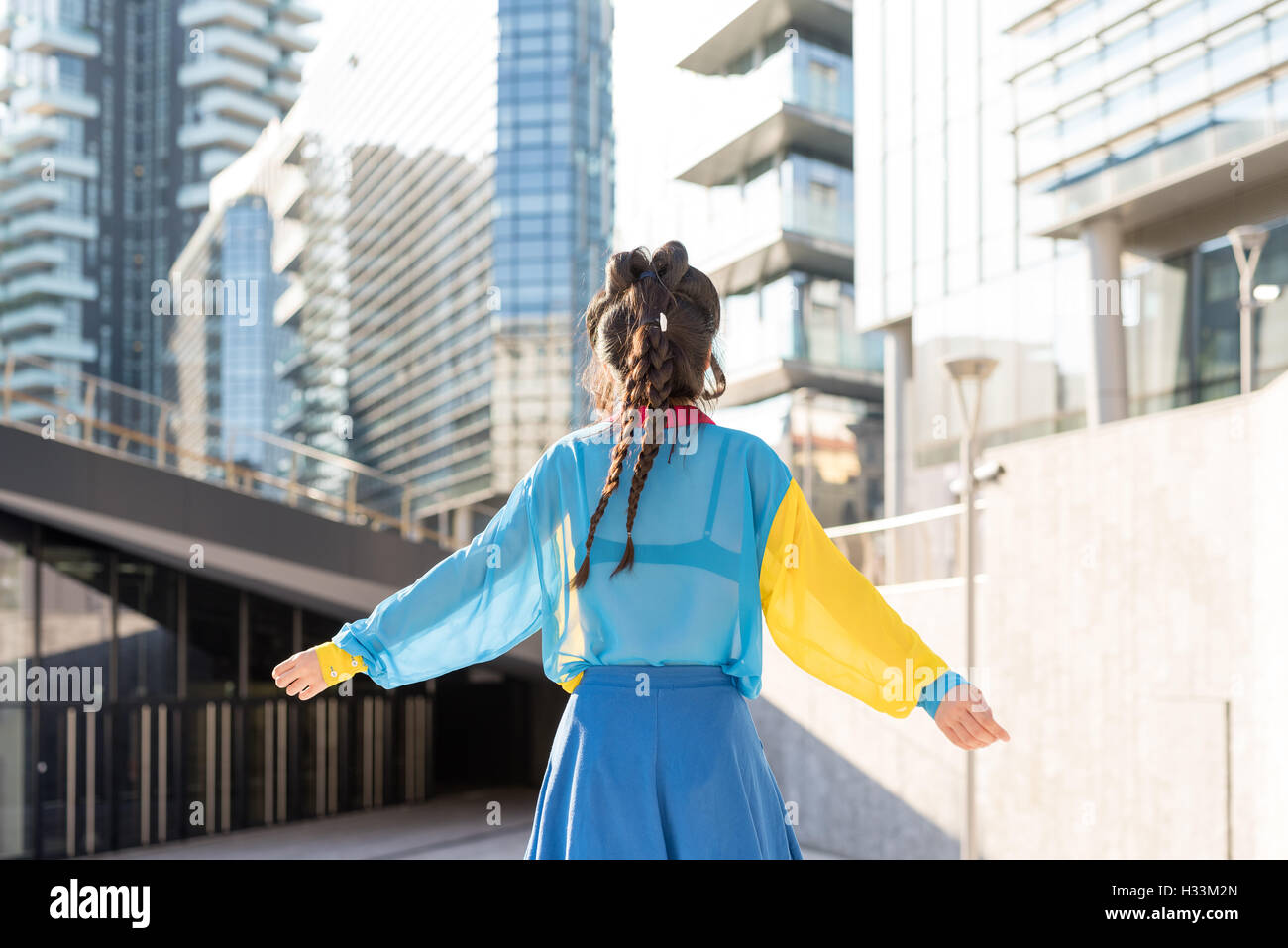 Back view of young woman with arms wide open outdoor in the city ...