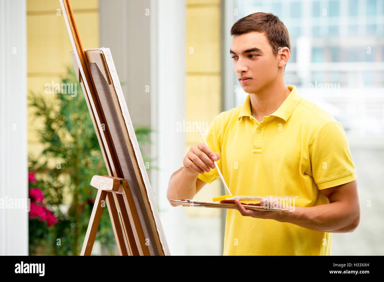 Young male artist drawing pictures in bright studio Stock Photo - Alamy