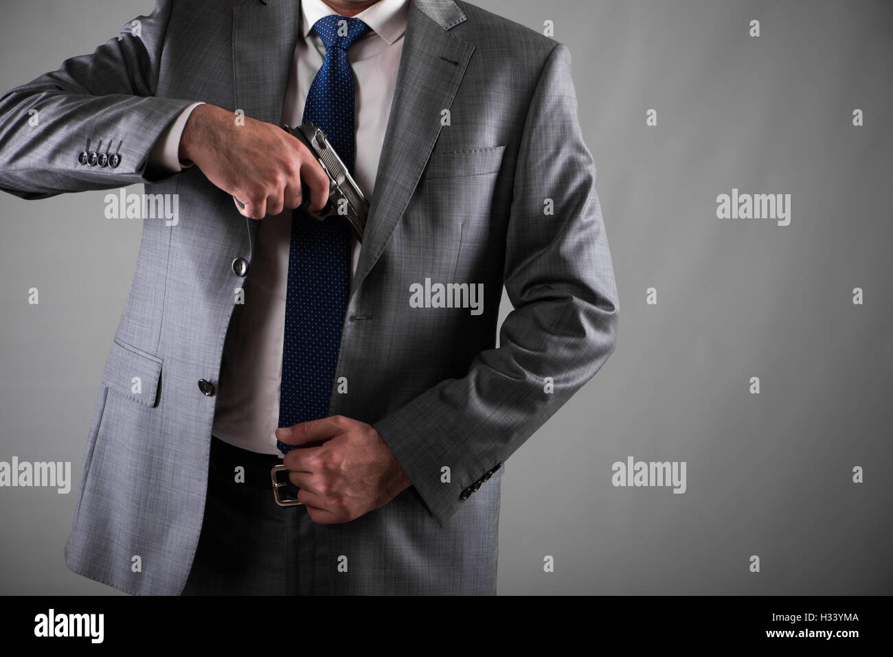 Man pulling out gun from his pocket Stock Photo - Alamy
