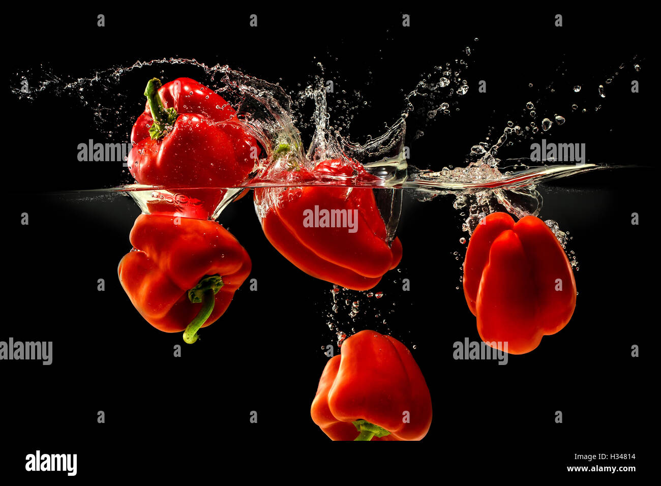 Group of bell pepper falling in water on black Stock Photo - Alamy