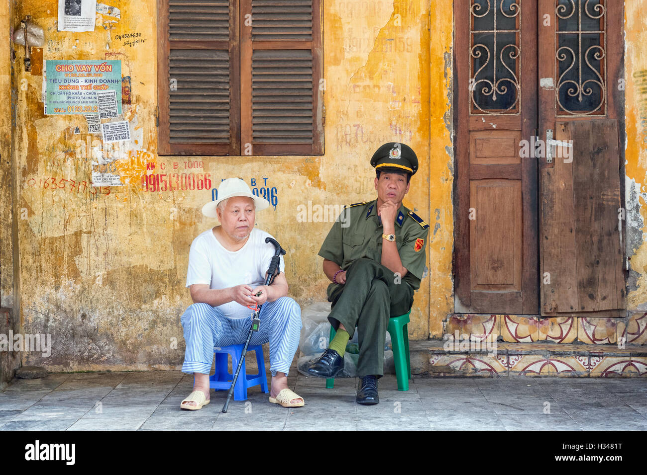 Policeman and man sitting on the sidewalk in the streets of Hanoi ...