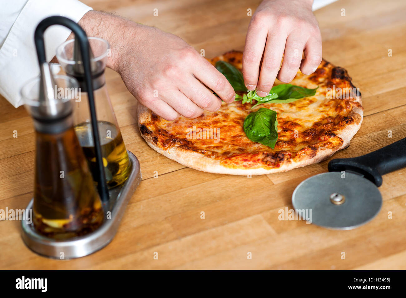 Chef giving finishing touch to pizza in kitchen Stock Photo - Alamy