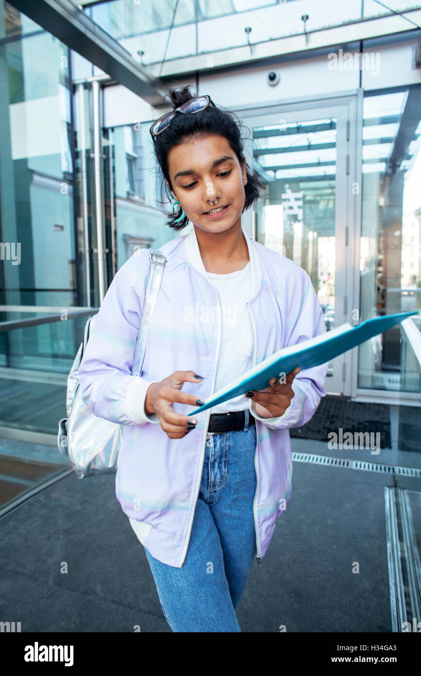 young cute modern indian girl at university building sitting on stairs ...