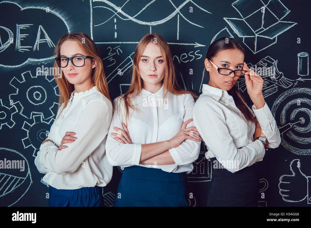 Two Europeans and Asian business women standing on a dark background ...