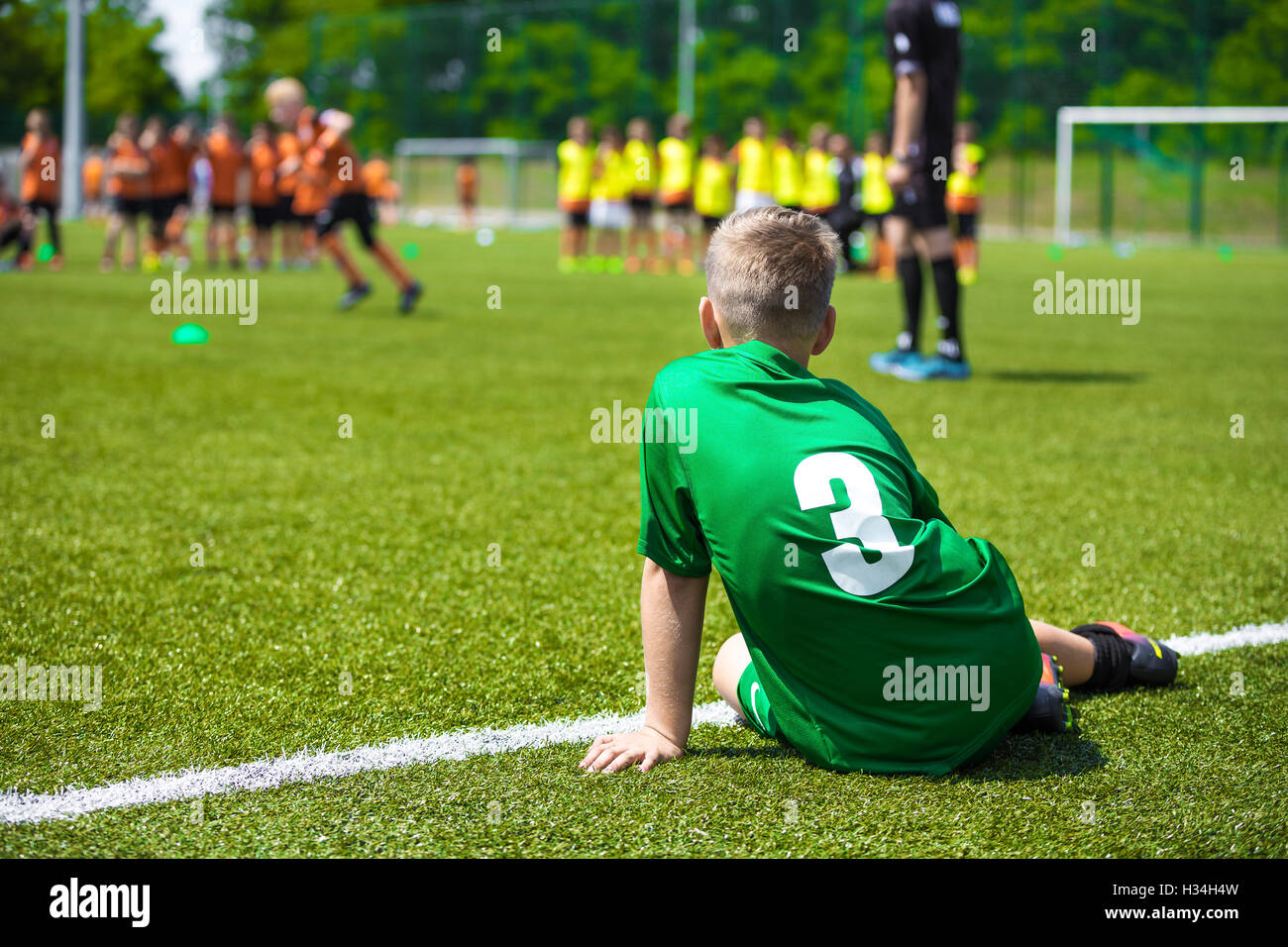Young caucasian soccer player sitting on grass. Youth football ...