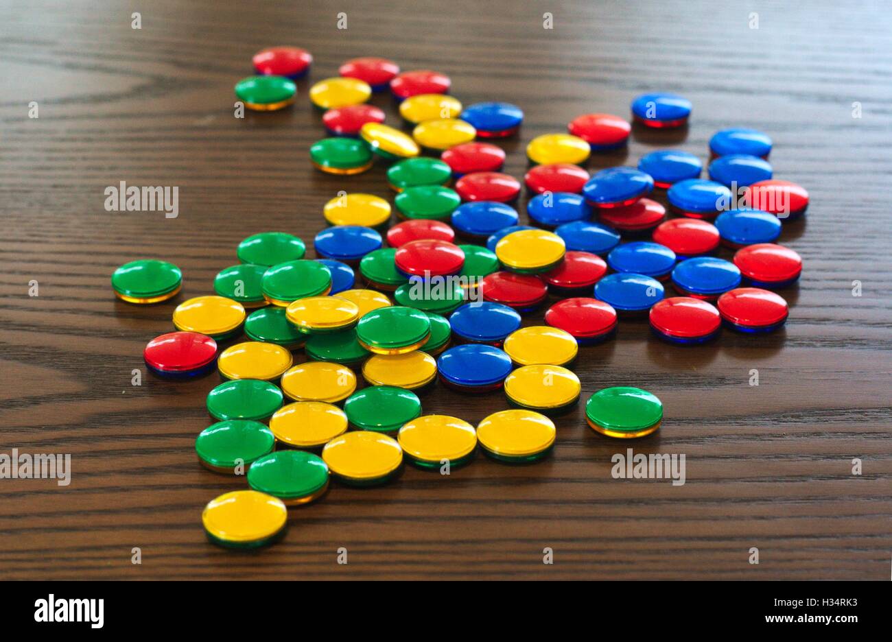 Brightly colored game counters scattered across a fake wood table top ...
