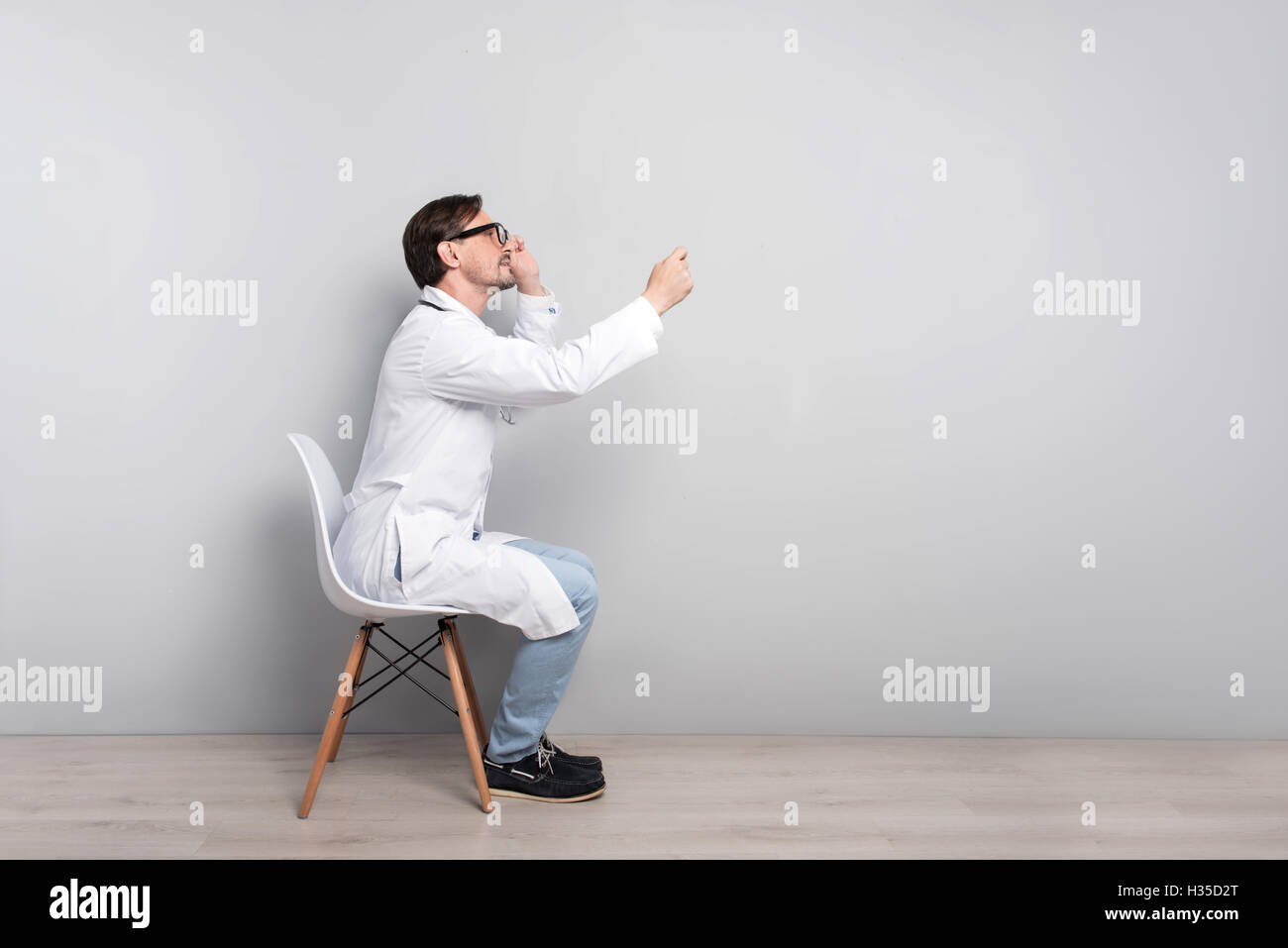 Concentrated doctor sitting on a chair with stethoscope Stock Photo - Alamy