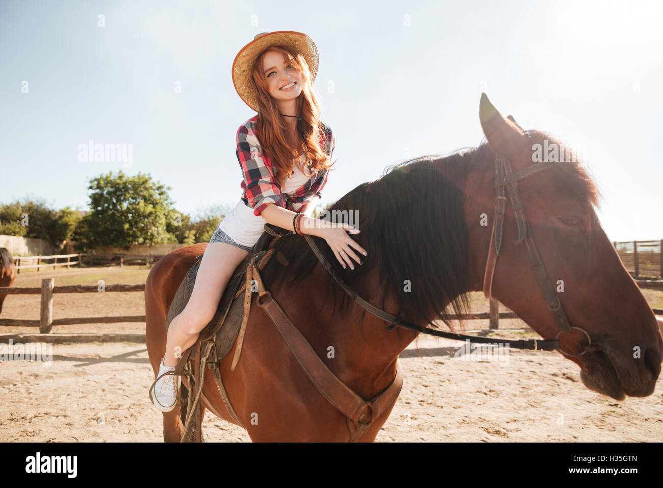 Happy pretty young woman cowgirl riding horse on ranch Stock Photo - Alamy