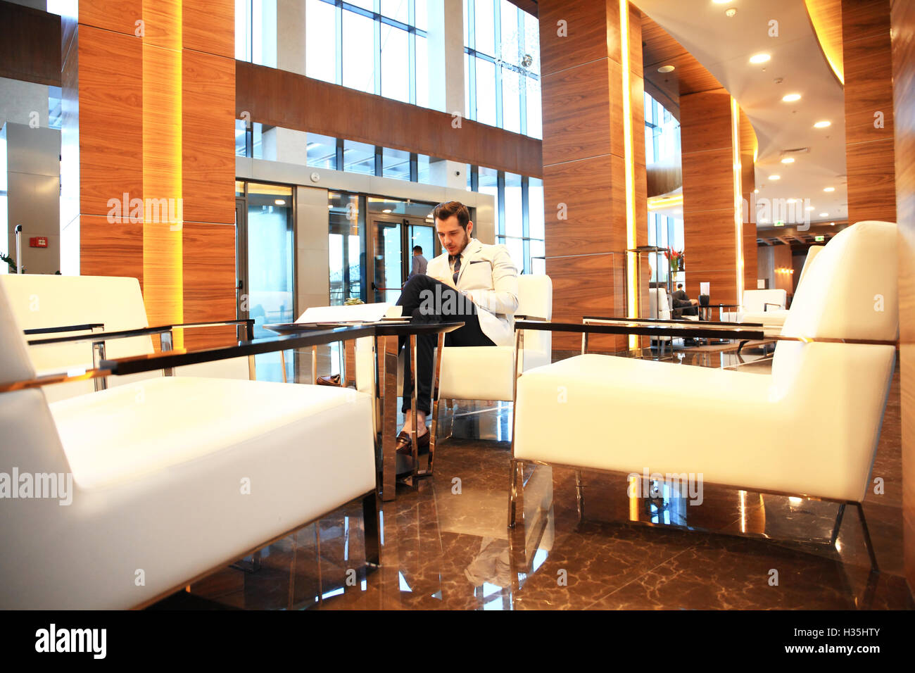 happy young businessman sitting on sofa in hotel lobby Stock Photo - Alamy