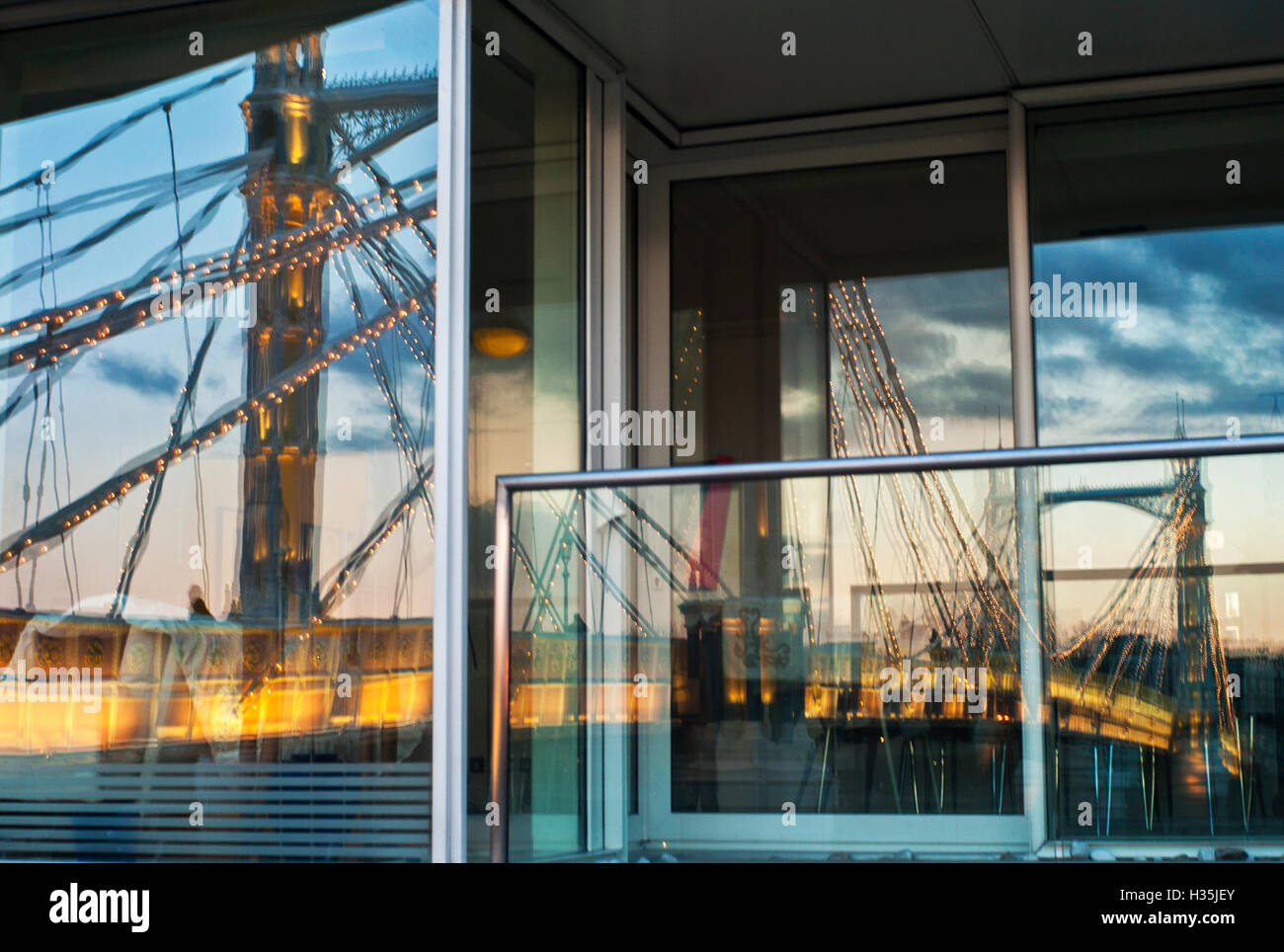 reflection in window of Albert Bridge illuminated at sunset over the ...