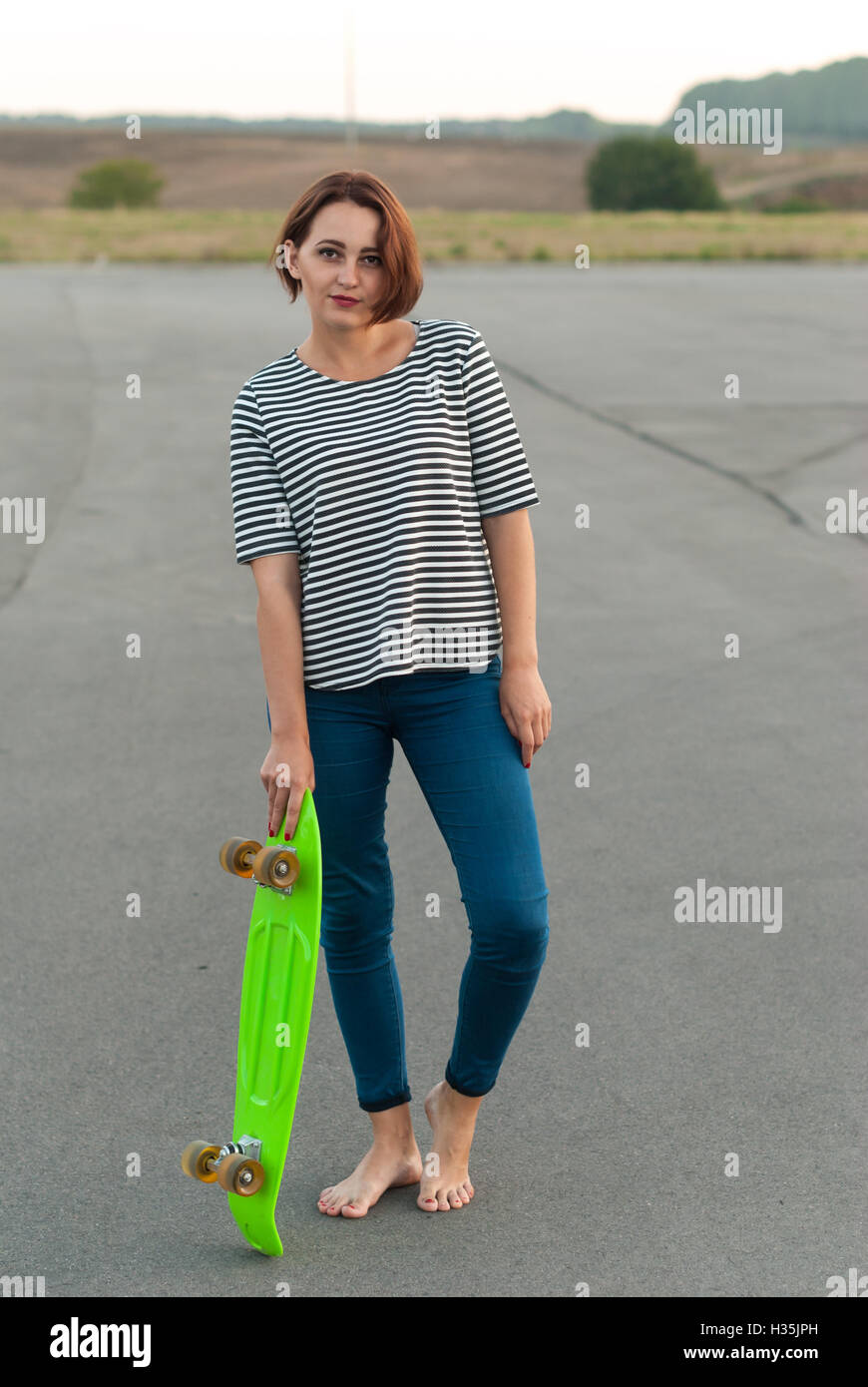 Girl standing barefoot on the asphalt with a skateboard Stock Photo - Alamy