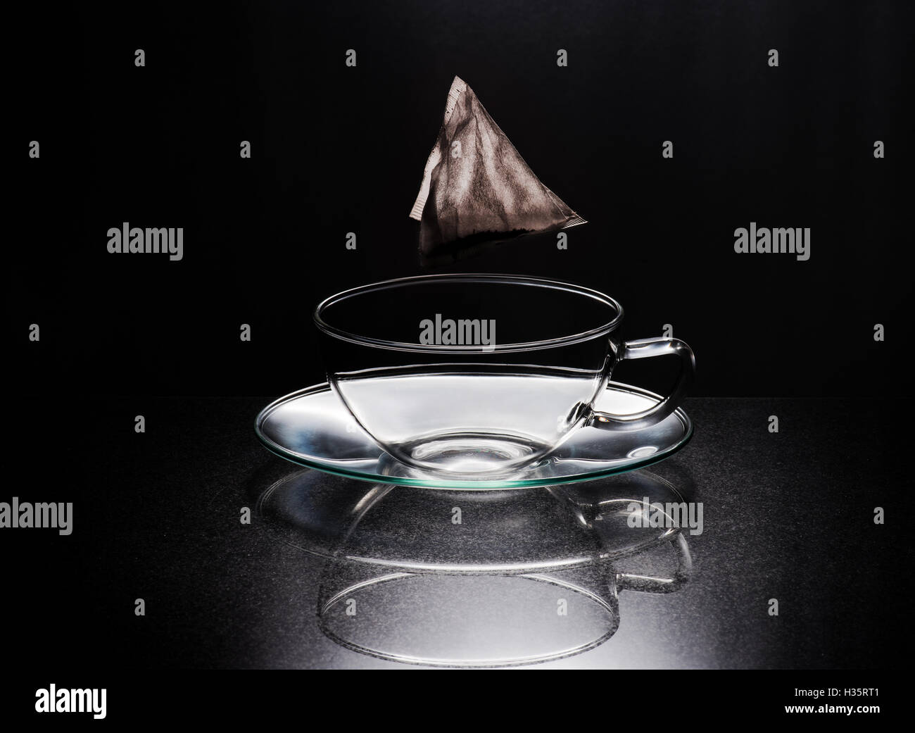 Tea Bag falling in to glass teacup and saucer Stock Photo - Alamy