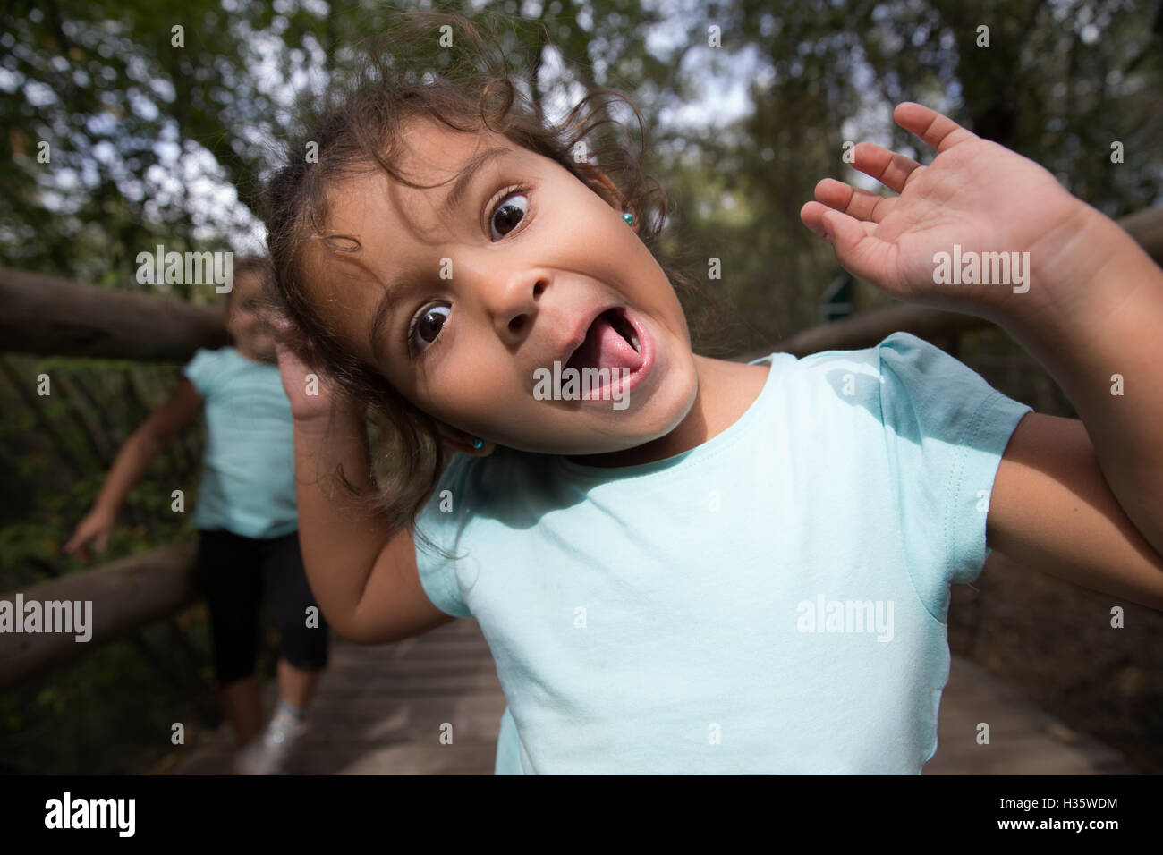 Portrait of cheerful little girl gesturing and making funny grimace at ...